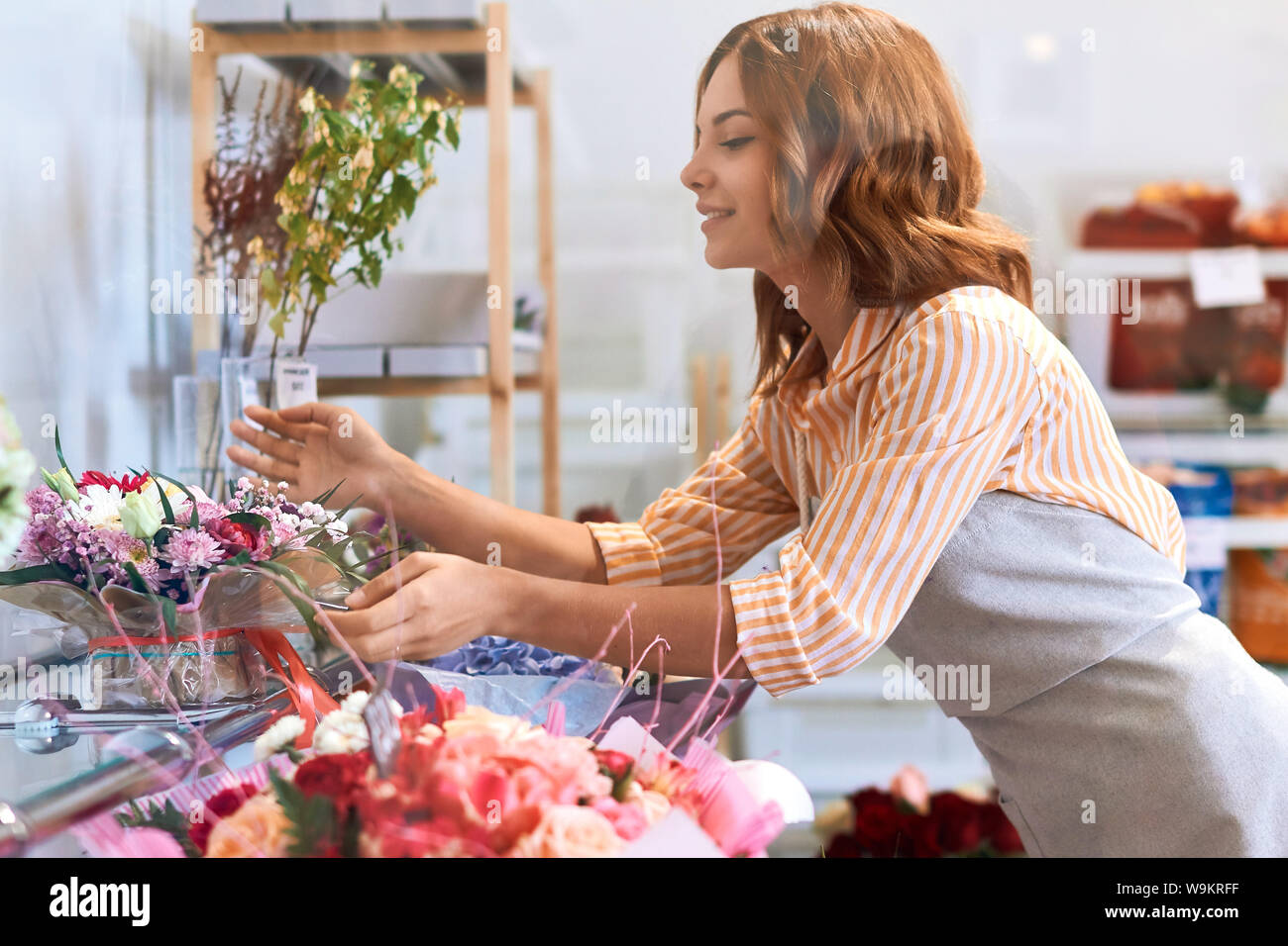 young pleasant florist enjoying the beauty of her flowers, pleasure ...