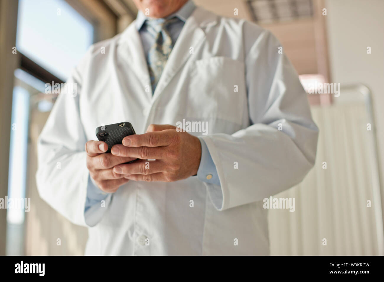 Doctor checking his mobile phone Stock Photo - Alamy