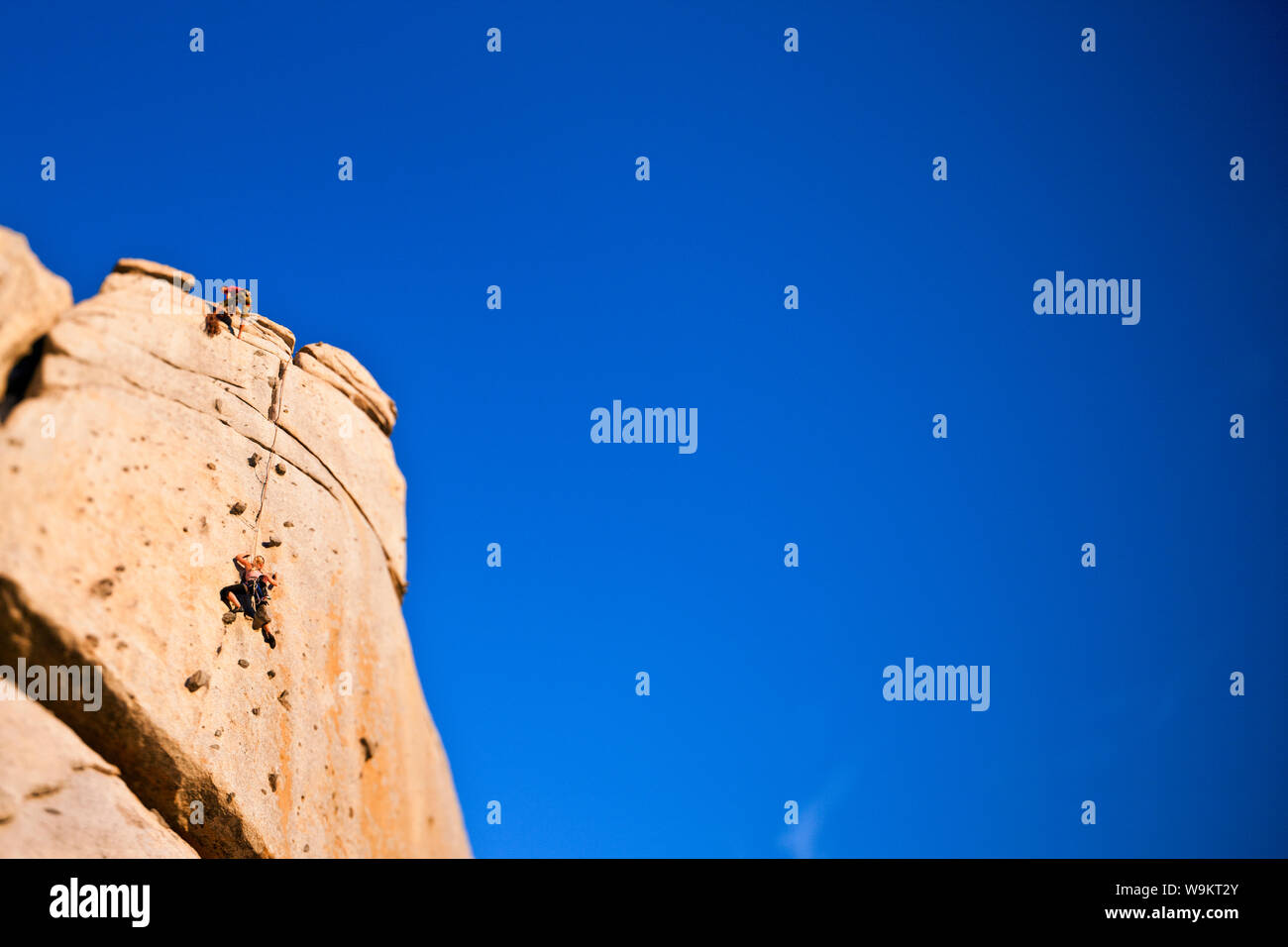Low-angle view of two rock climbers climbing on mountain top Stock ...
