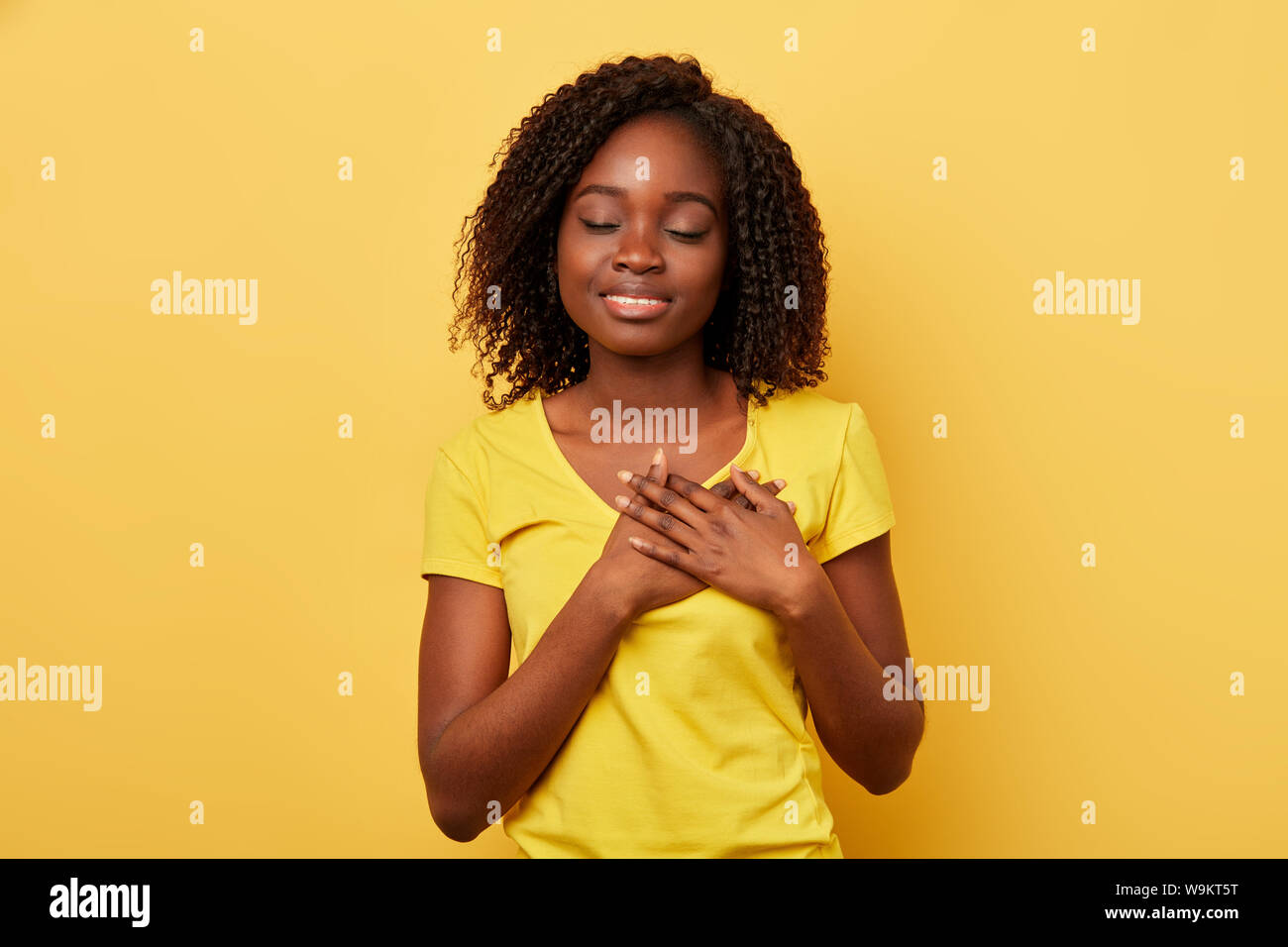 emotional calm woman with closed eyes, keeps hands on chest, expresses ...