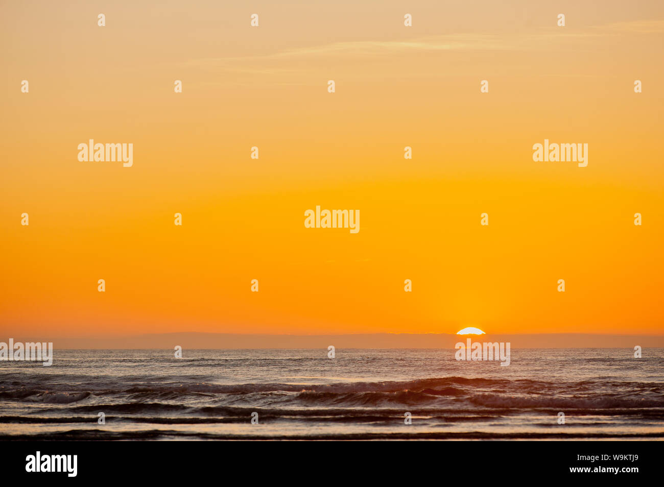Sun setting over the ocean Stock Photo - Alamy