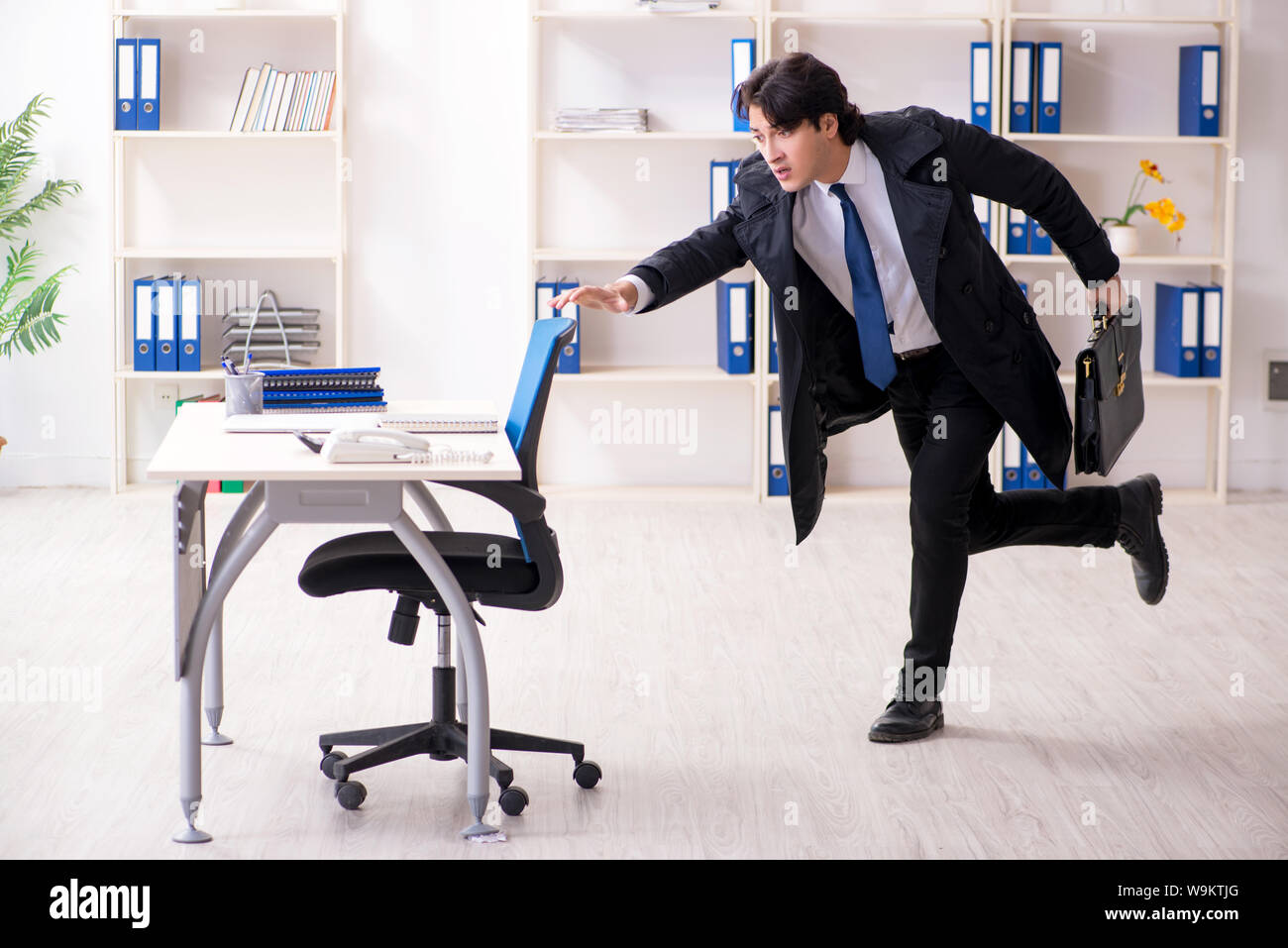 The young male employee in the office in time management concept Stock ...