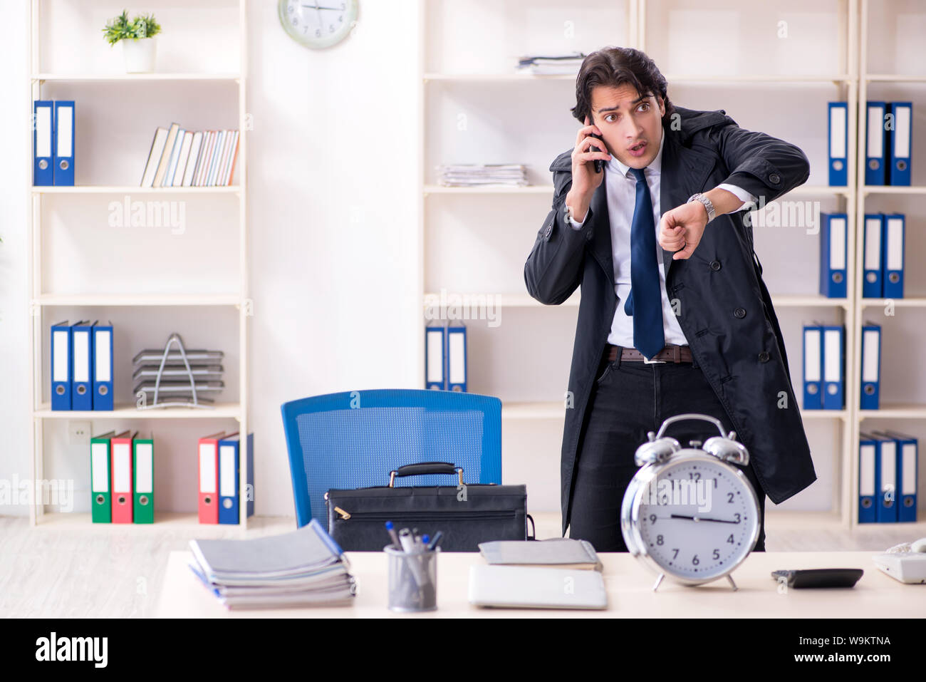 The young male employee in the office in time management concept Stock ...