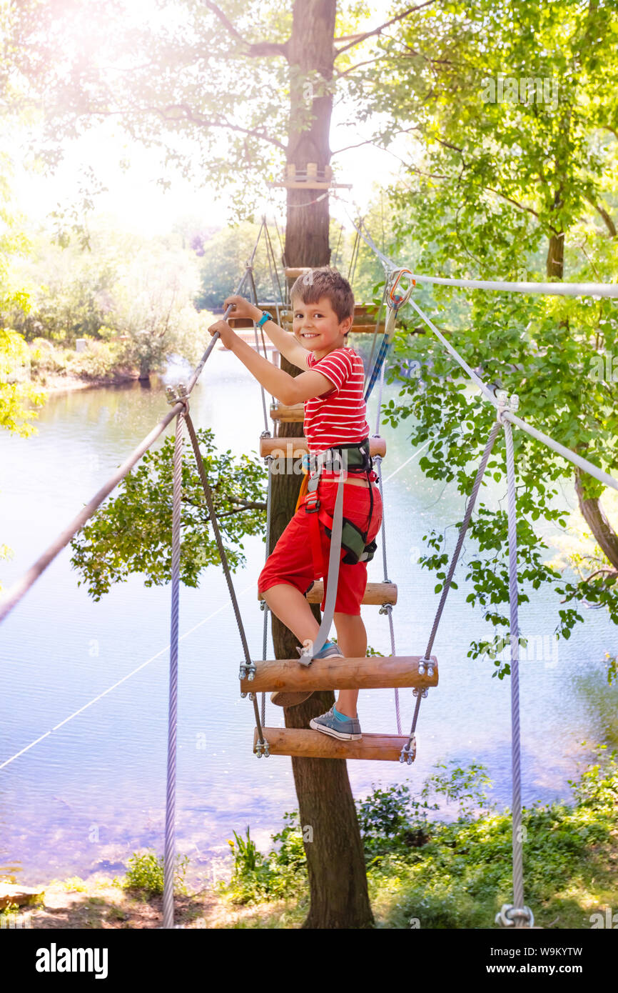 Boy and high tree rope bridge in adventure park Stock Photo - Alamy