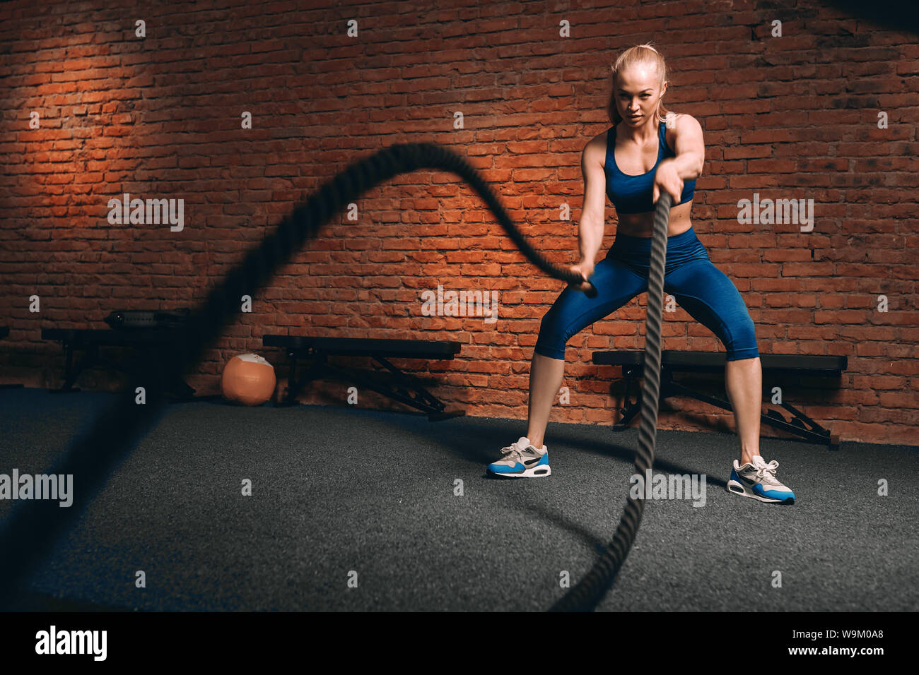 muscular cool girl performing battle rope exercises. flying ropes, copy ...