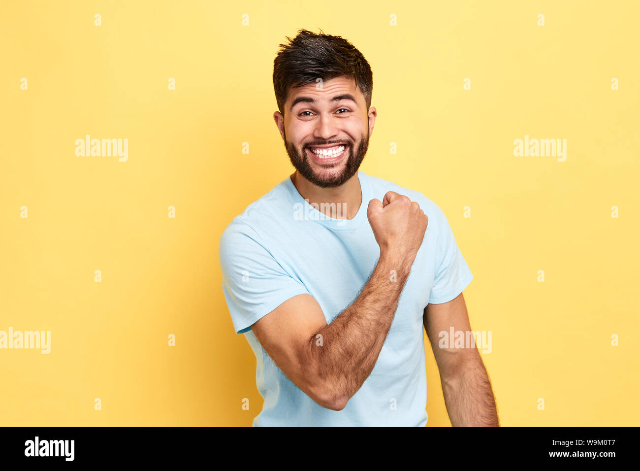 handsome man is happy and excited, doing winner gesture with arm raised ...