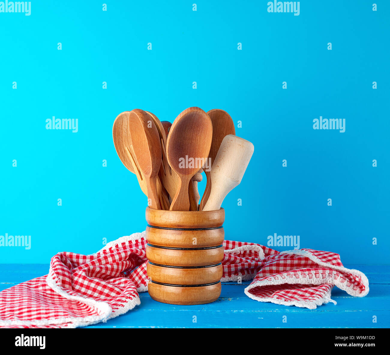 wooden spoons in a wooden container on a blue table, kitchen backdrop ...