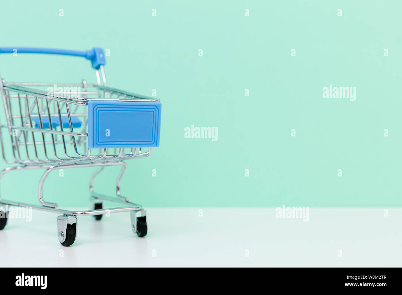 Empty shopping cart on light blue background Stock Photo - Alamy