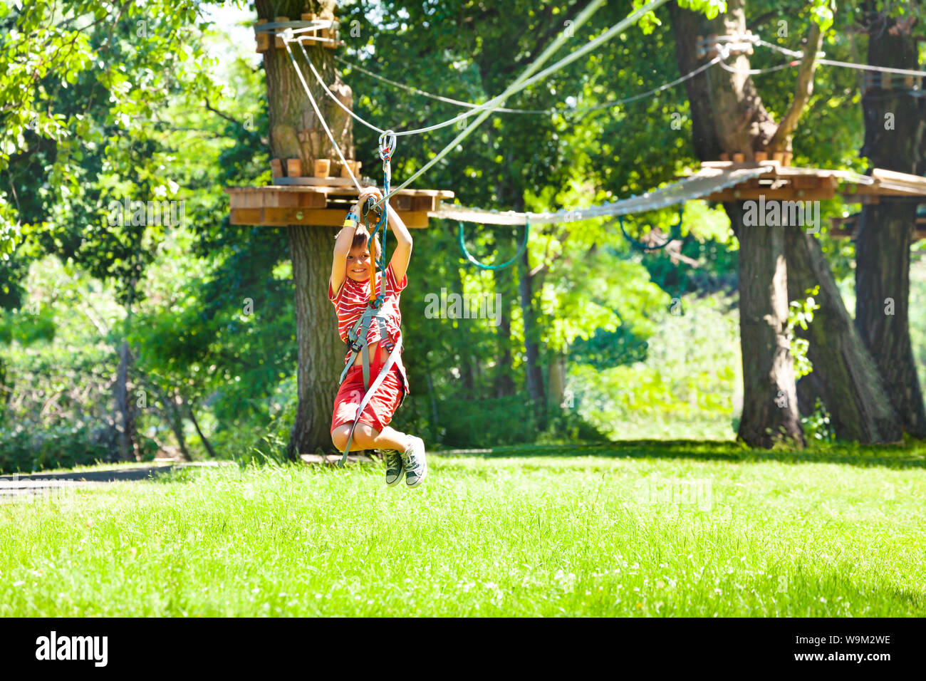 Boy at easy low zip line for kids, adventure park Stock Photo - Alamy