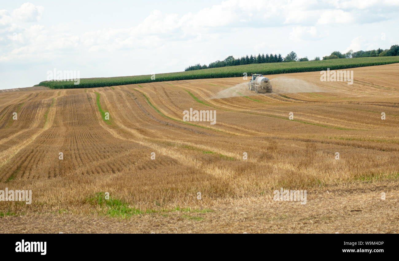 a tractor on which a trailer filled with liquid manure hangs drives ...