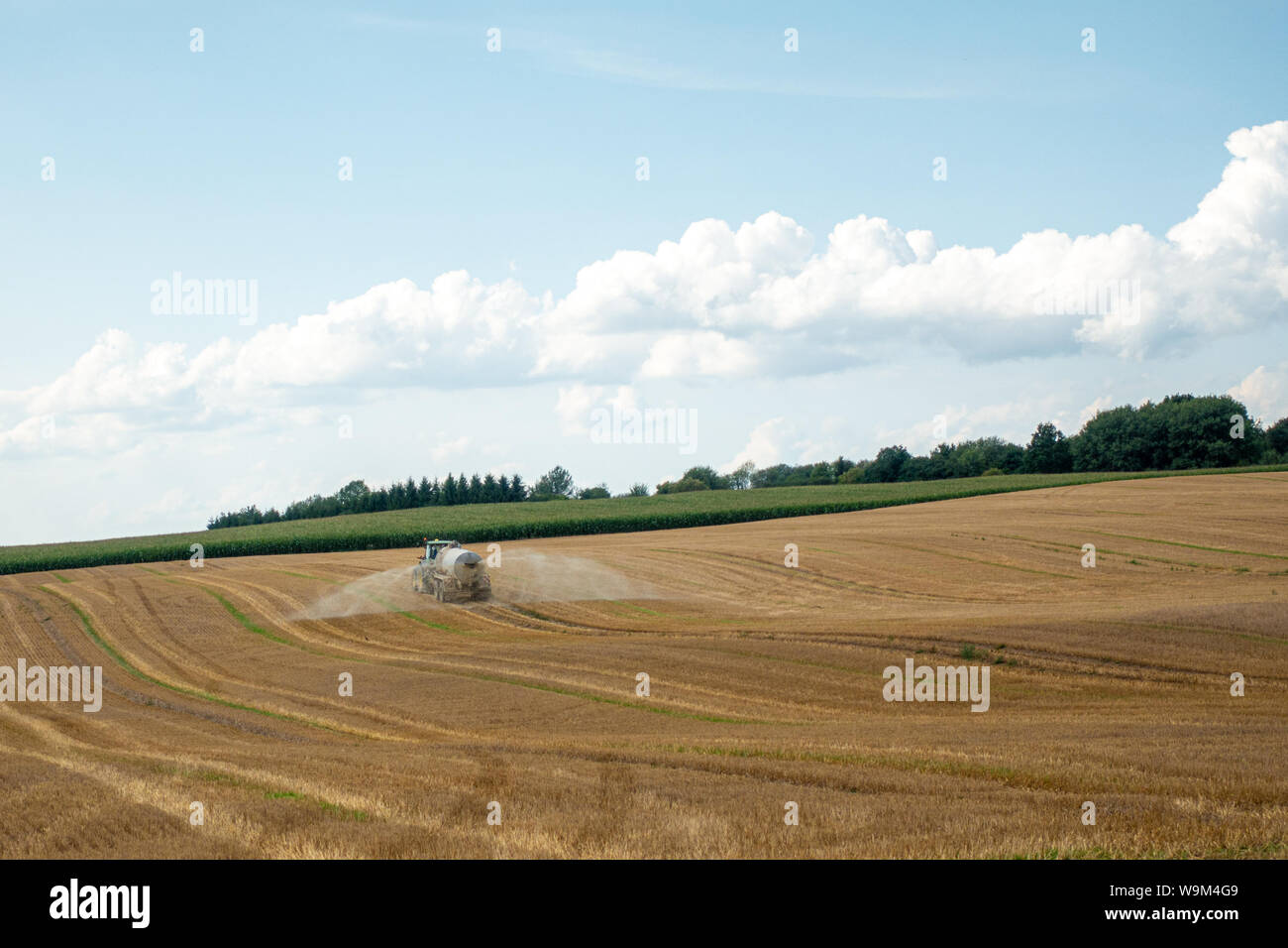 a tractor on which a trailer filled with liquid manure hangs drives ...