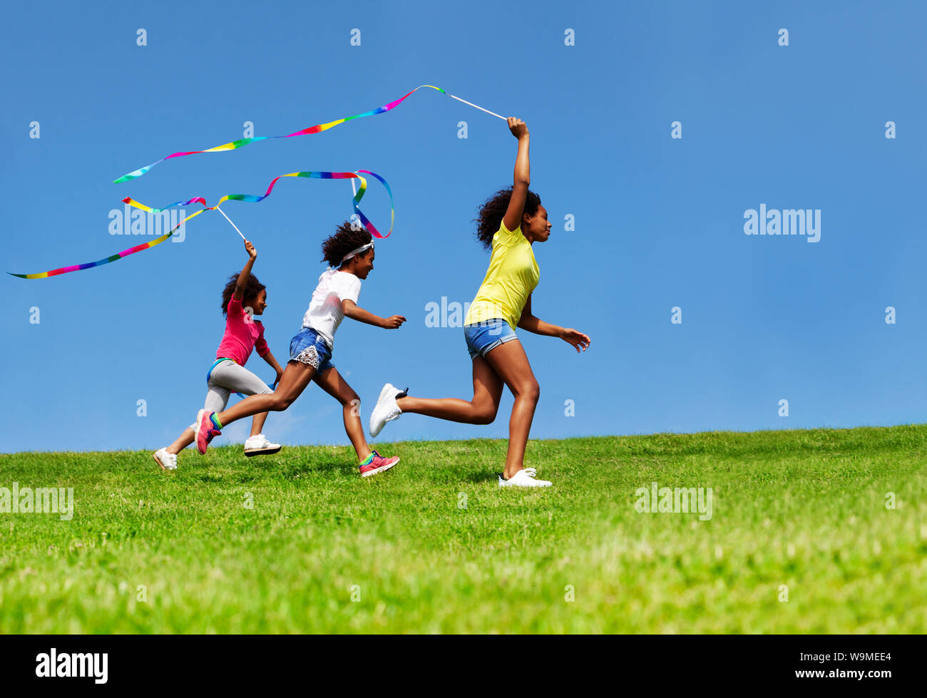 Happy three girls jump, wave with ribbon over sky Stock Photo - Alamy