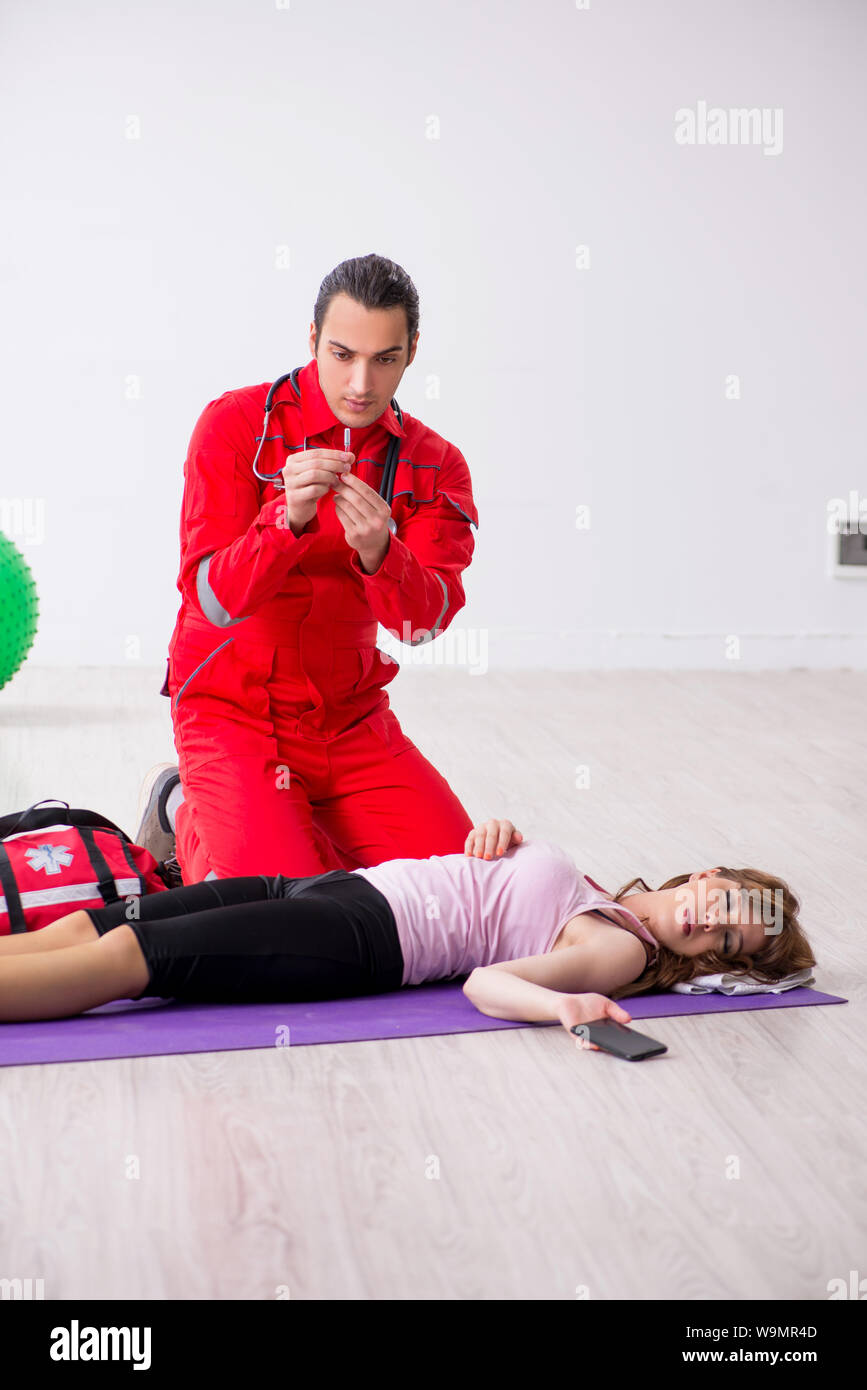 The paramedic in red visiting young woman in gym Stock Photo - Alamy