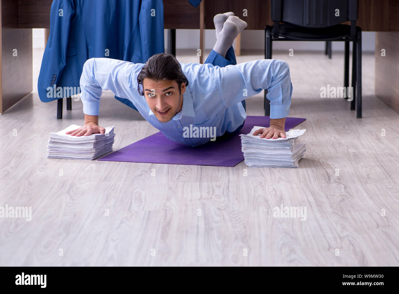 The young handsome businessman doing exercises at workplace Stock Photo ...
