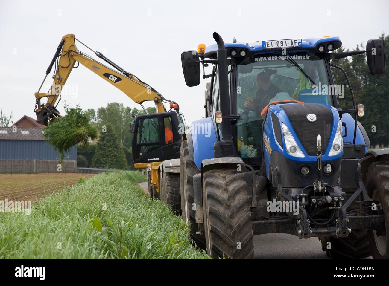 A tractor, trailer and excavator aligned to dig away, and remove the ...