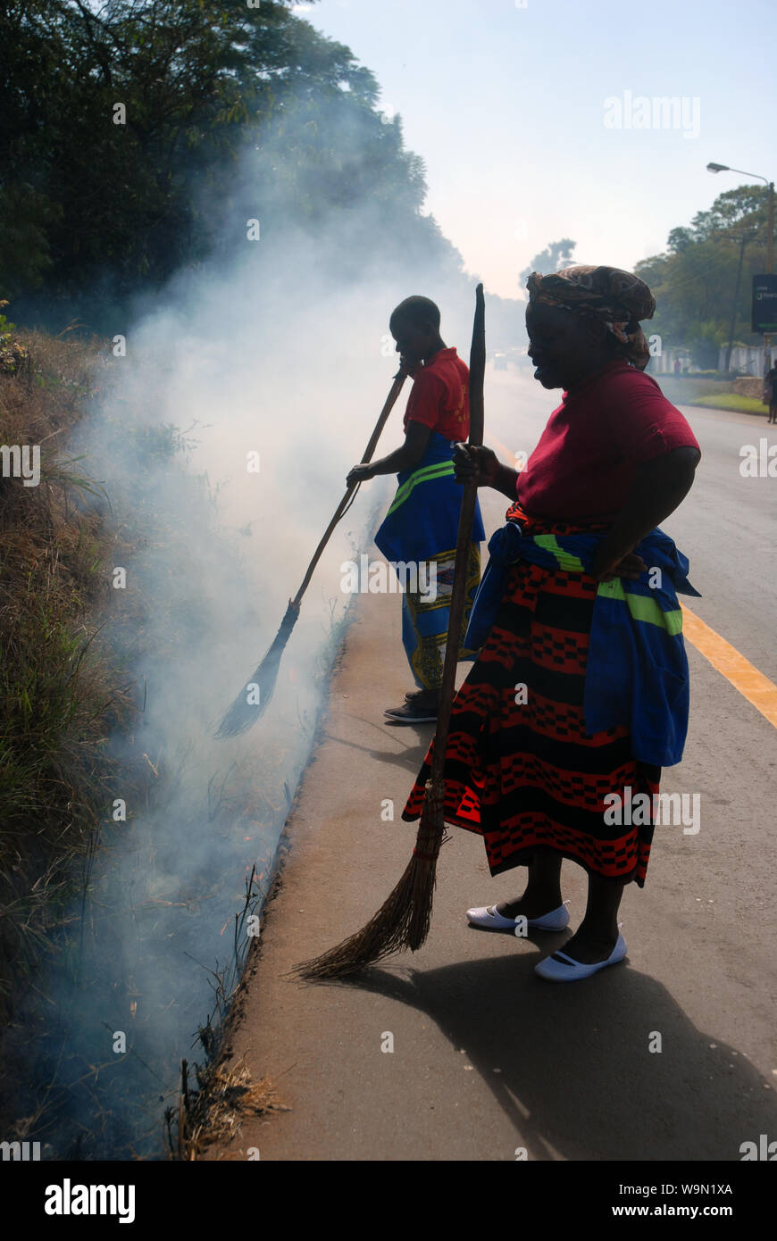 Two ladies burning leaves and rubbish in roadside ditch, Lilongwe ...