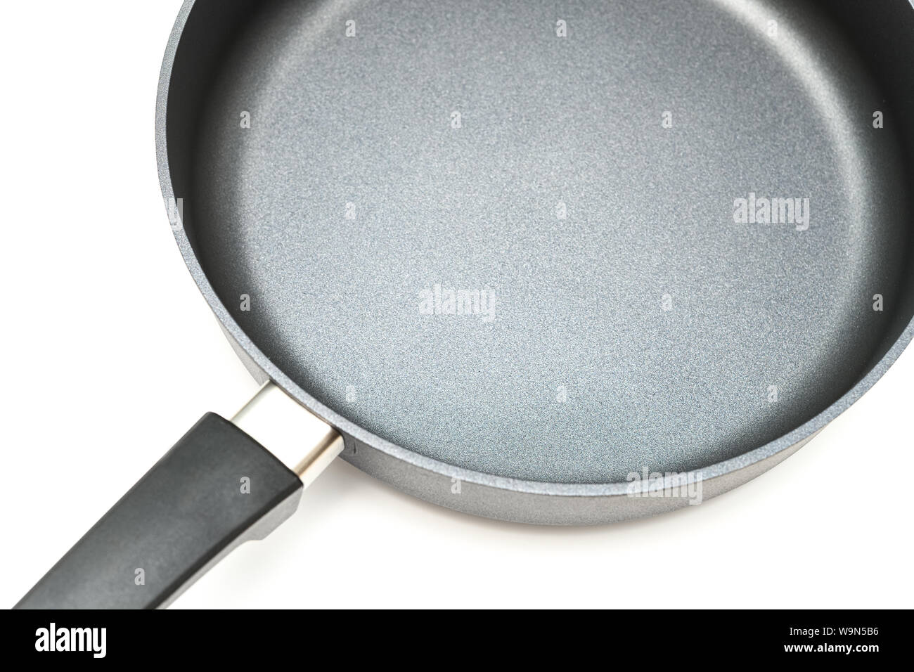 part of a brand new matt black stainless steel pan on white background ...