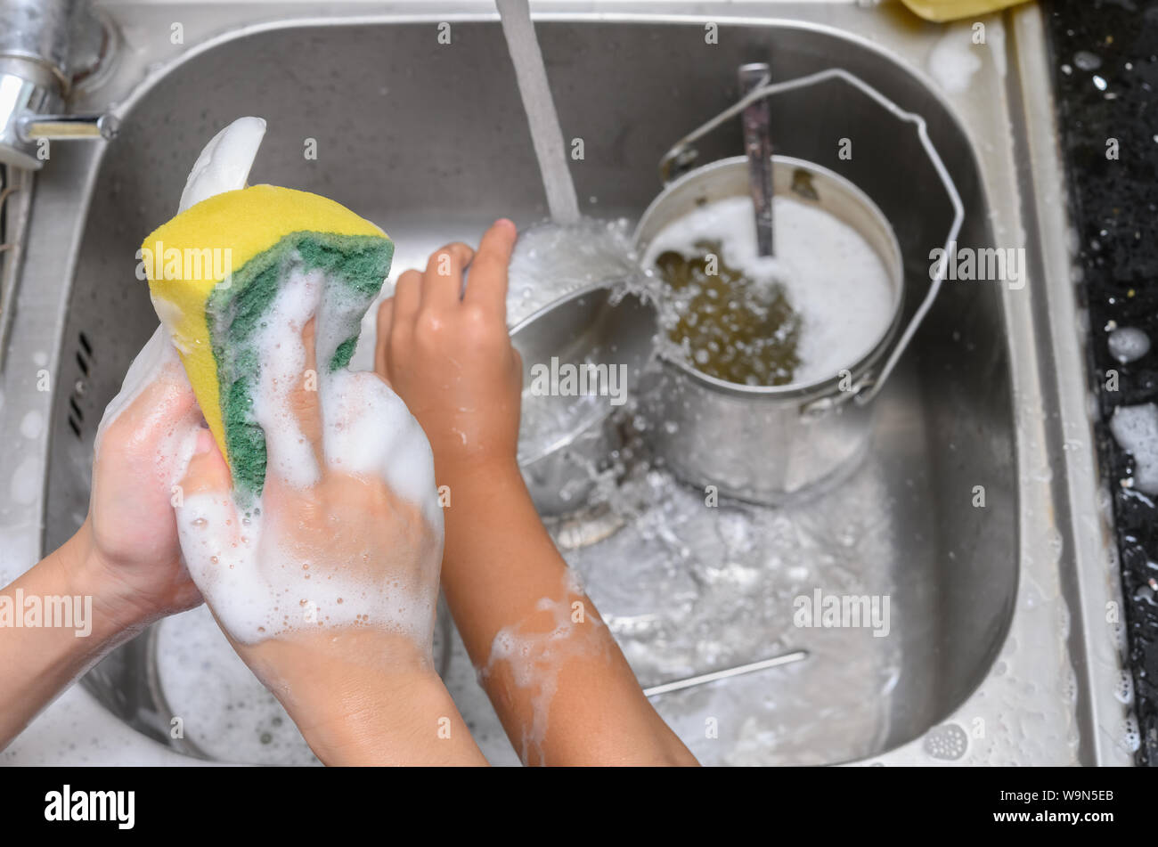 kids washing dishware in the kitchen sink with soapy sponge Stock Photo ...