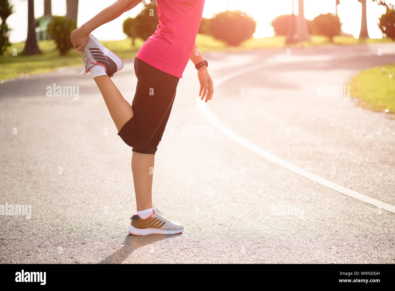 Young Fitness Woman Runner Stretching Legs Before Run In The Park