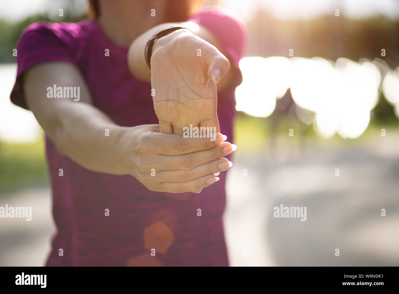 Young fitness woman runner stretching hand before run in the park ...