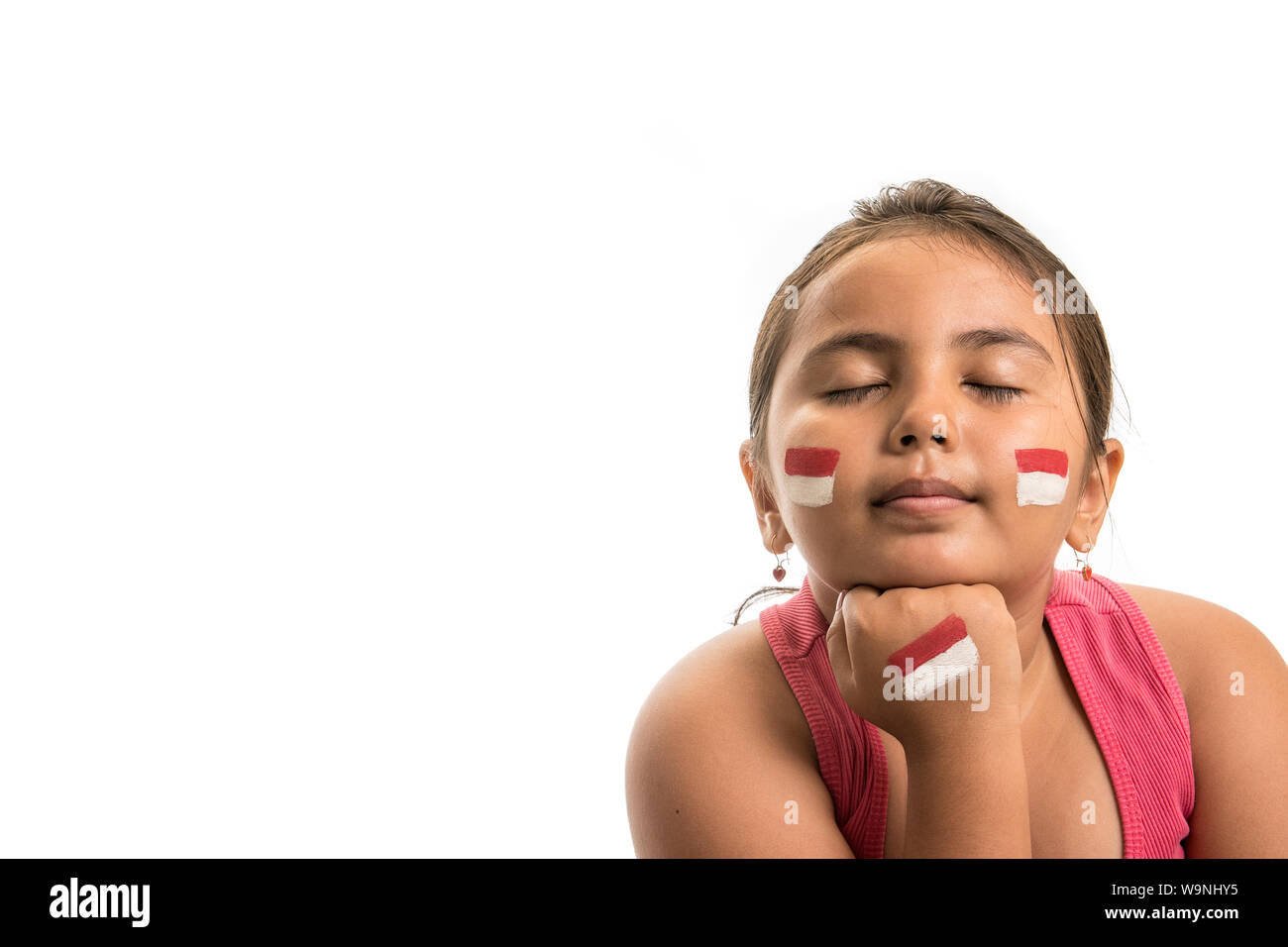 Young Indonesian girl with painted Indonesian flag on her face looking ...