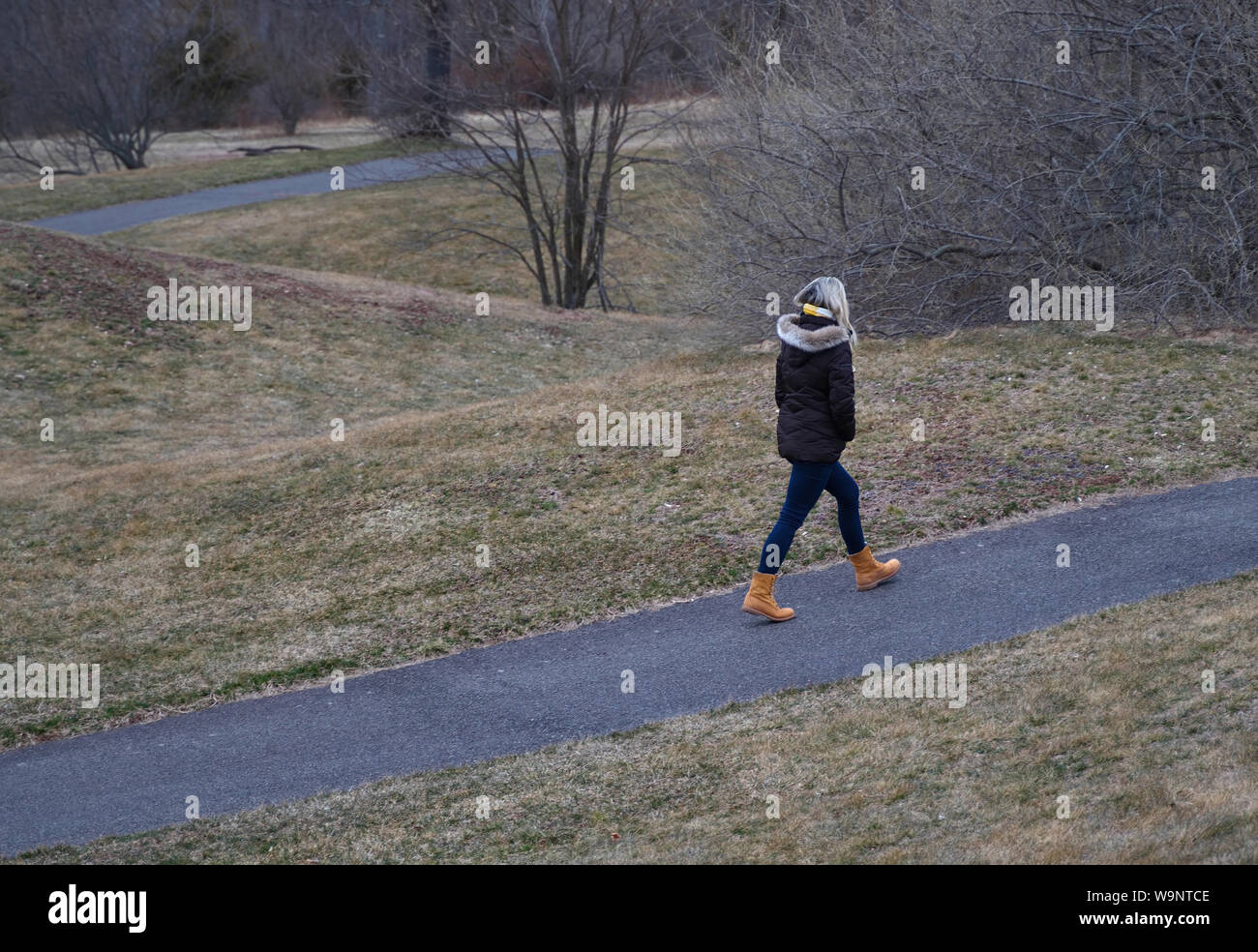 Young woman in cold weather gear taking a walk in the park despite the ...