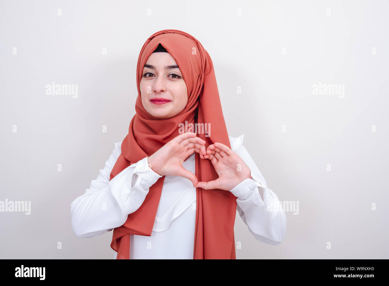 Young hijab muslim woman making a heart gesture with her fingers ...