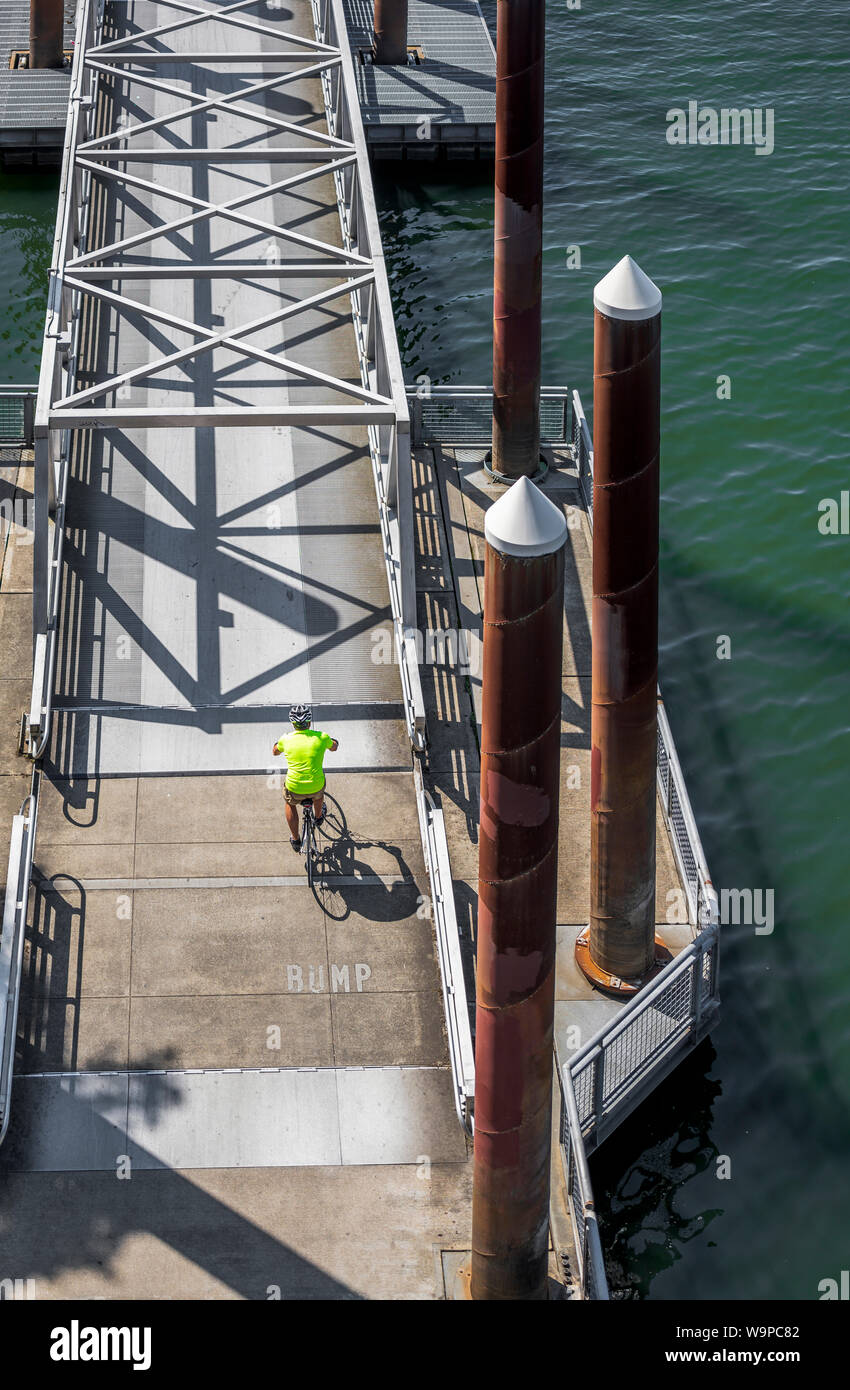 Man rides a bike on a bike path crossing a mobile ramp on a floating ...