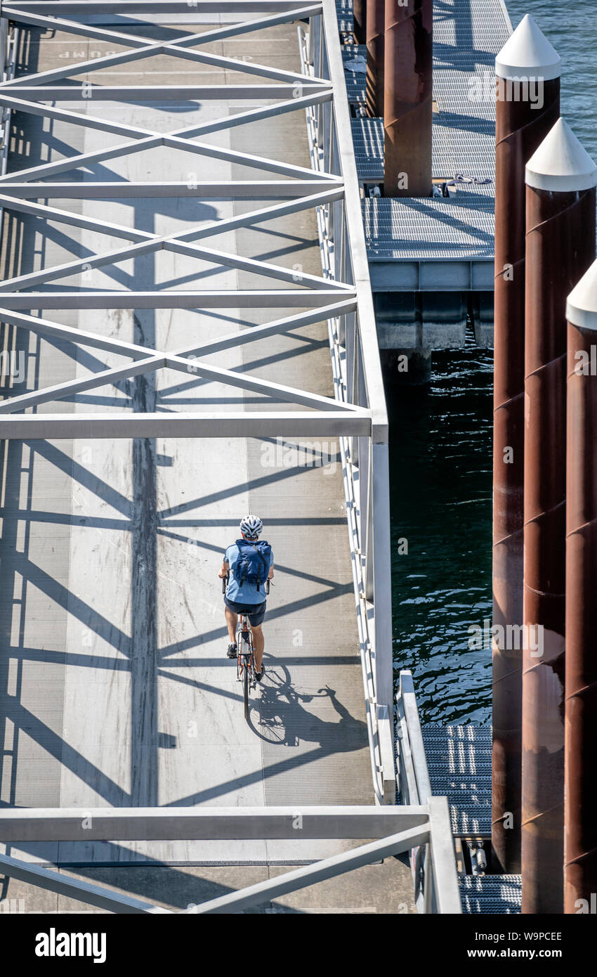 Man rides a bike on a bike path crossing a mobile ramp on a floating ...
