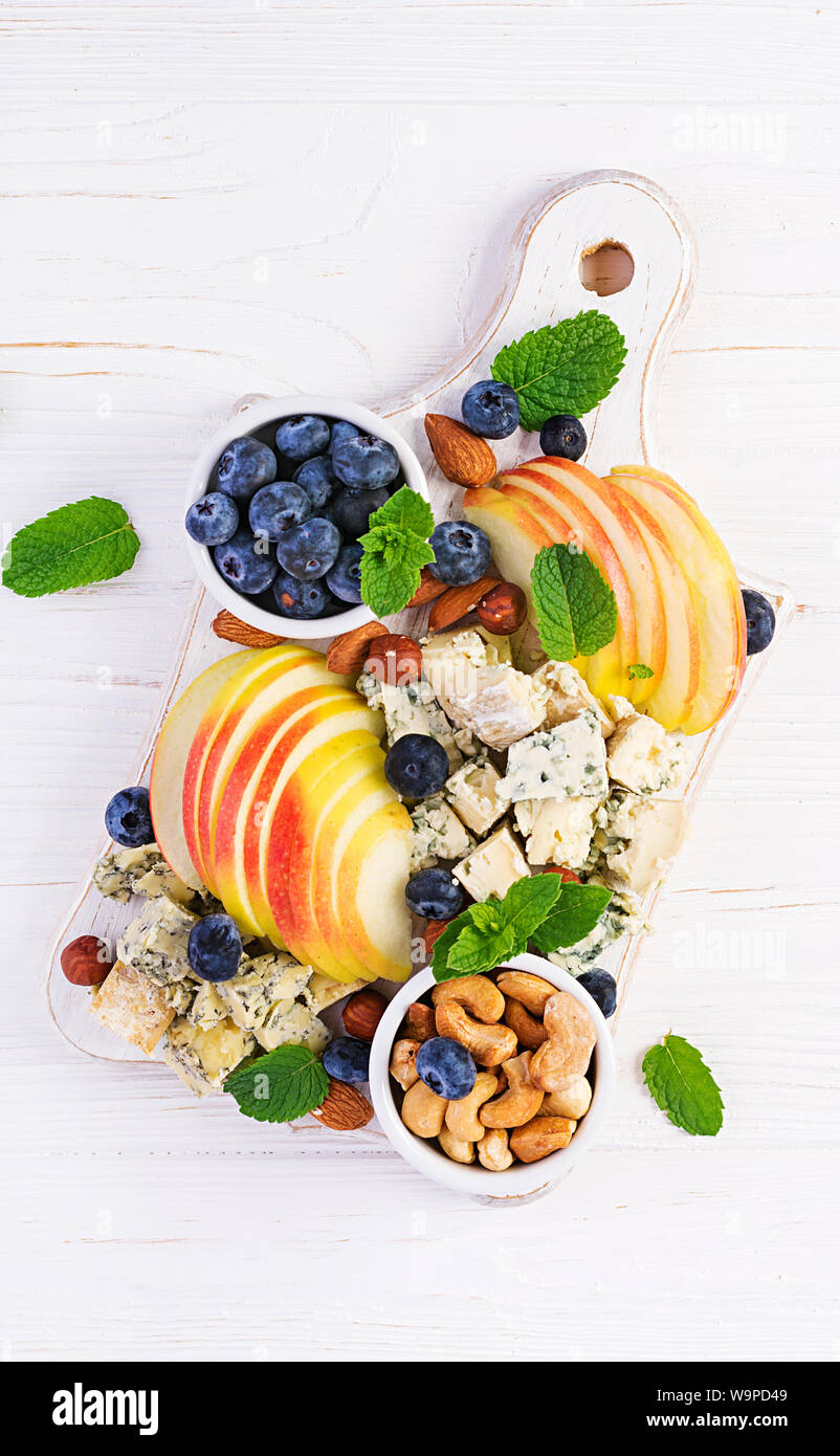 Cheese platter with assorted cheeses, blueberry, apples, nuts on white ...