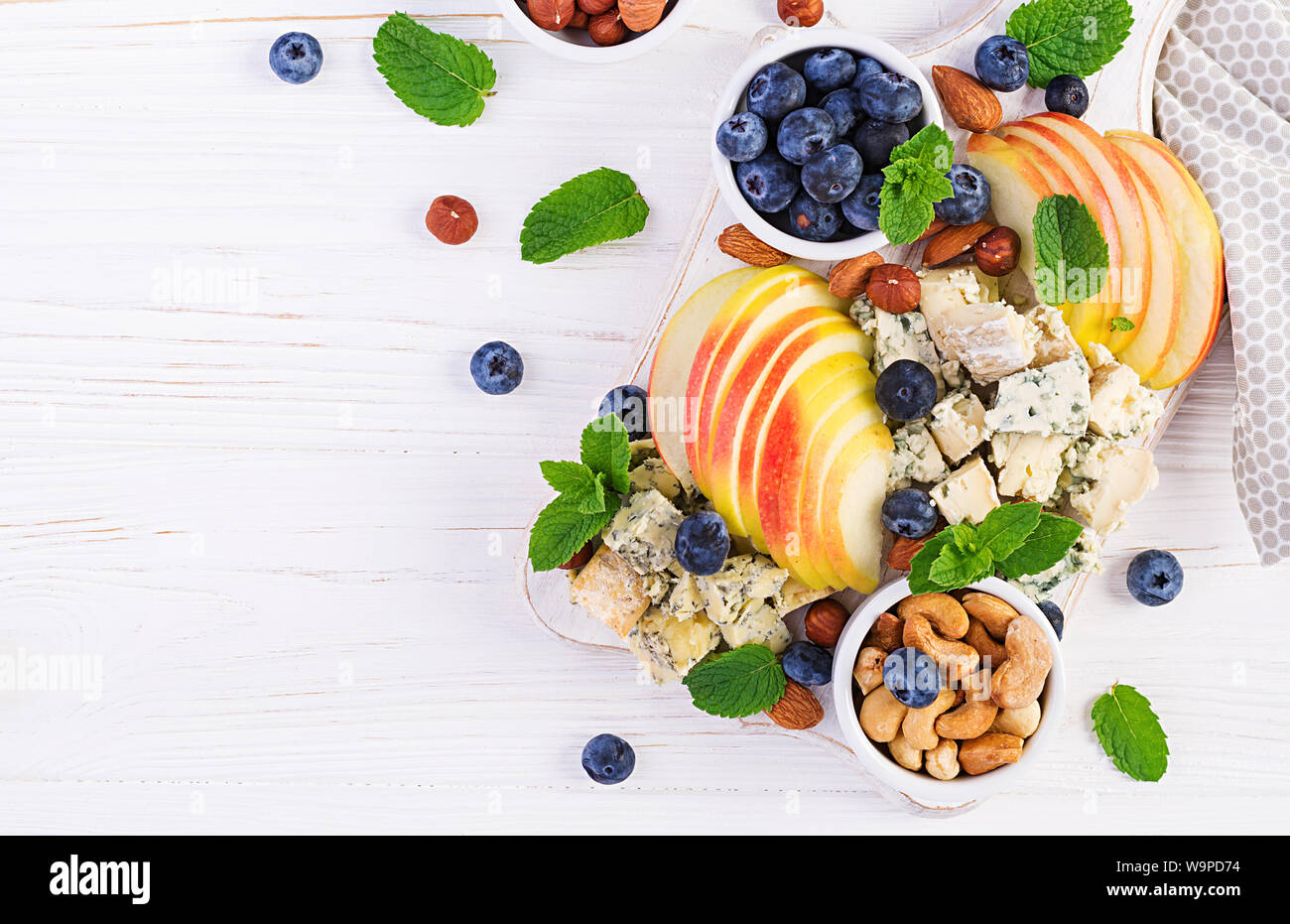Cheese platter with assorted cheeses, blueberry, apples, nuts on white ...