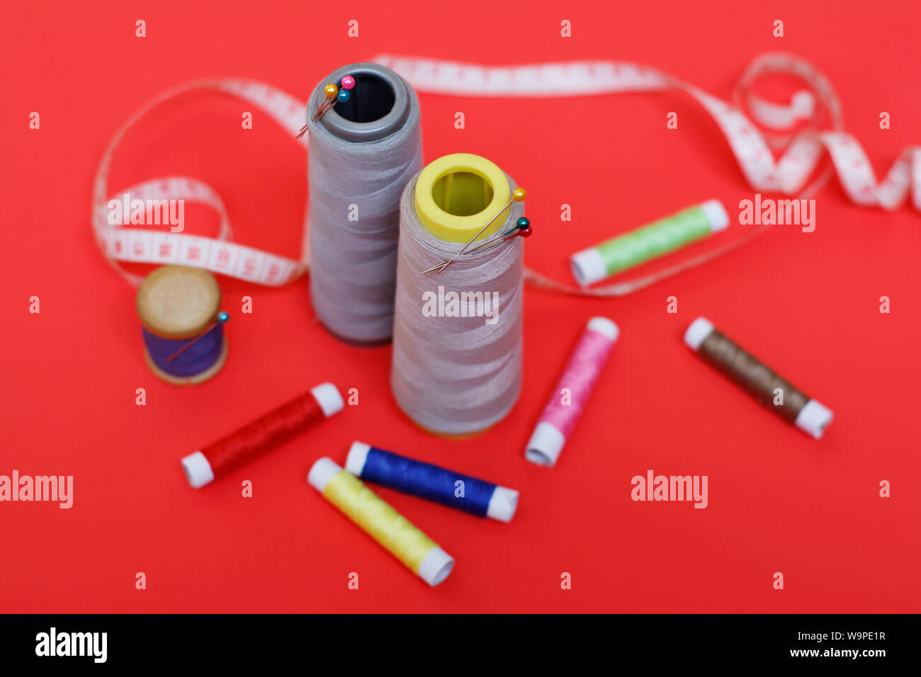 Composition with threads and sewing accessories on a red background ...