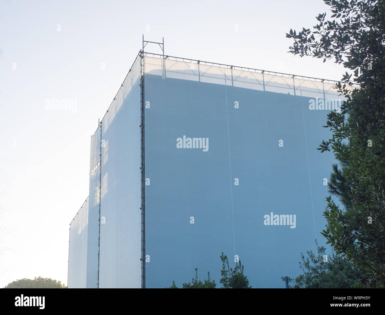 covered scaffolding protects a building under restoration, white sky ...