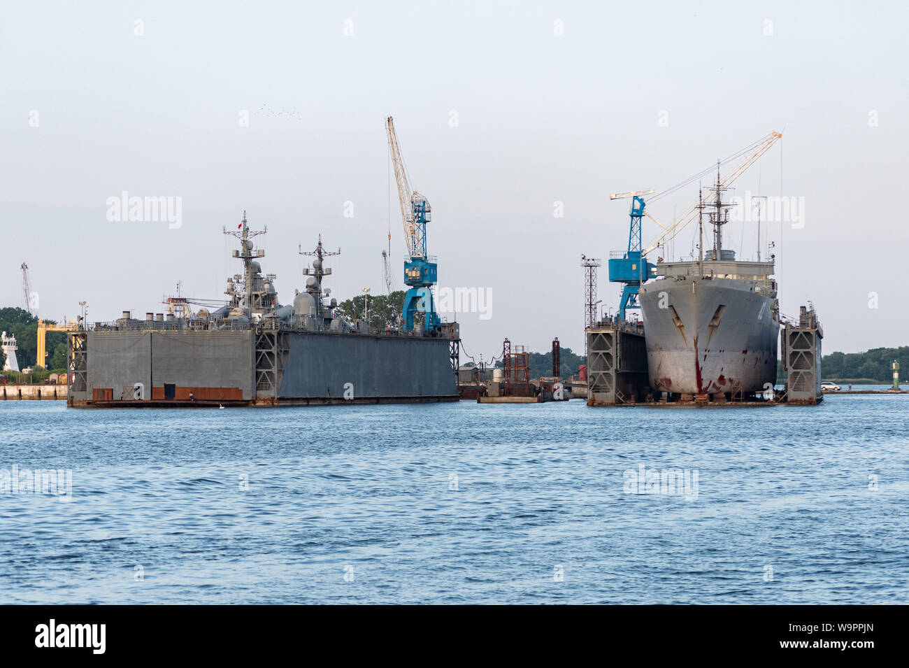 Large iron navy ships in shipyard for repair. Big crane in dockyard ...