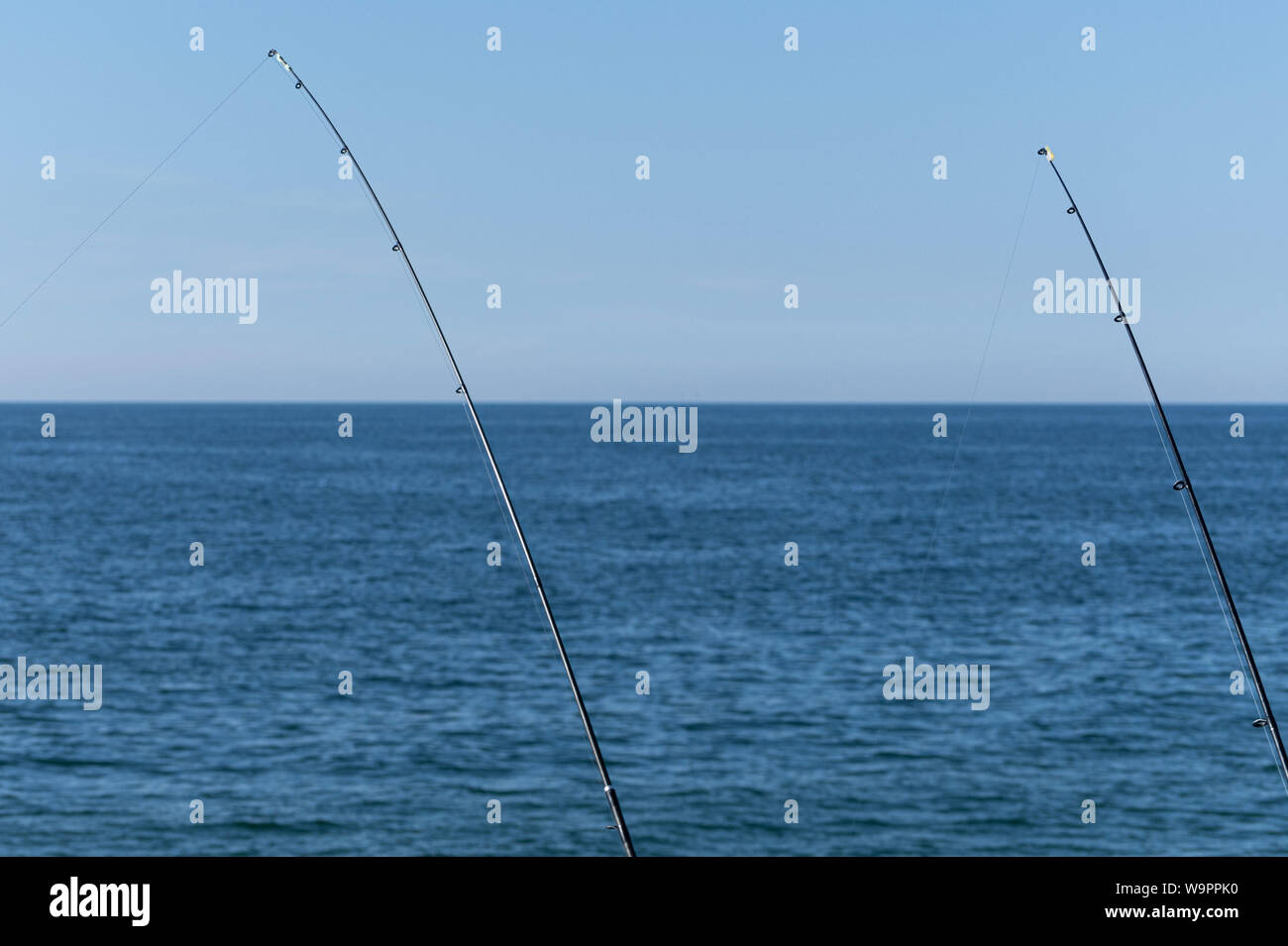 Two fishing rod against blue ocean or sea background, copy space ...