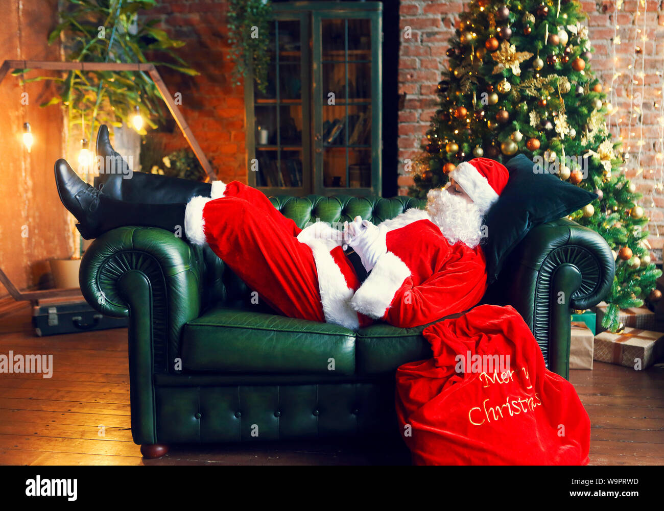 Santa Claus sleeping at home near Christmas tree on the green sofa ...