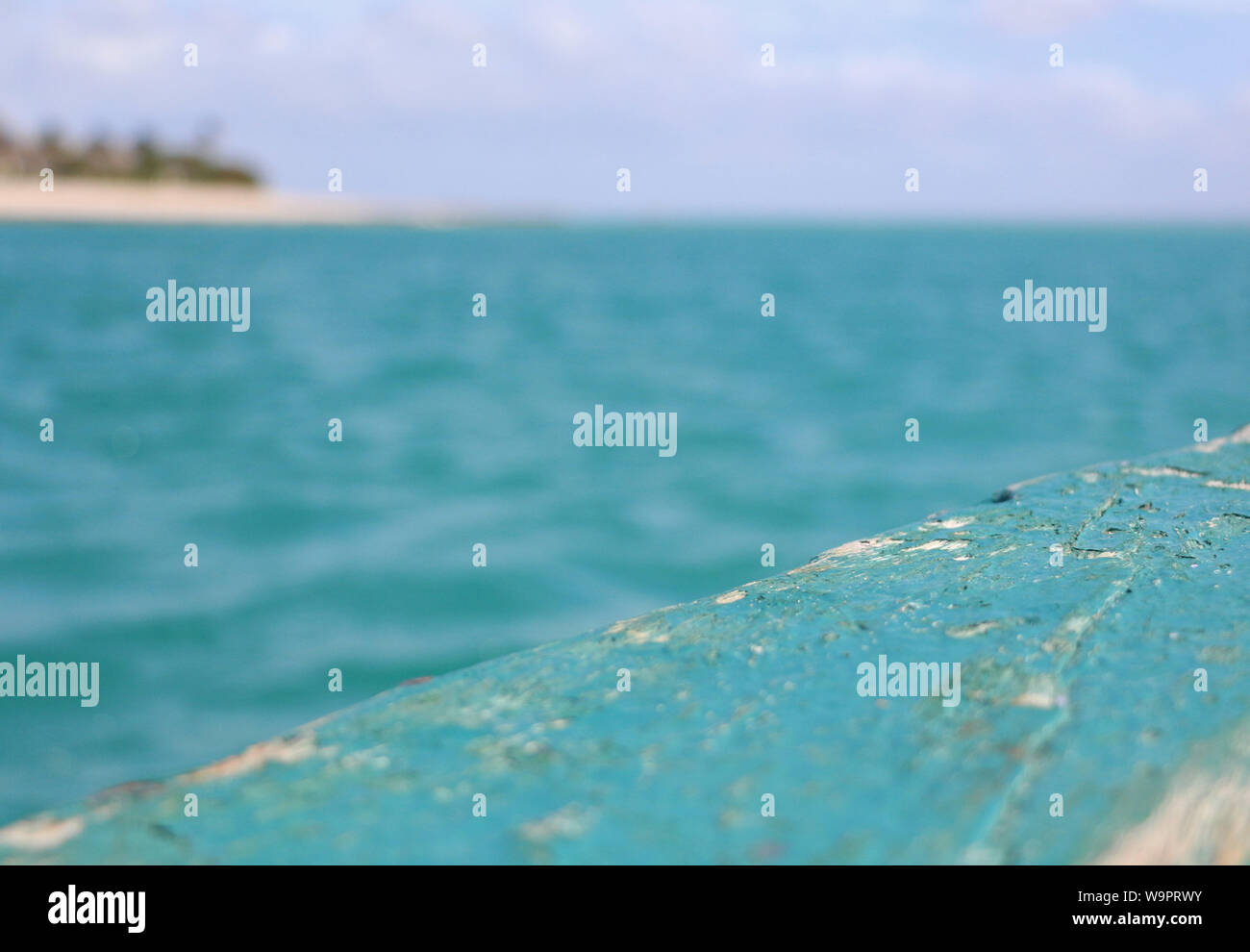 Close-up of edge of blue boat with Indian Ocean and tropical island ...