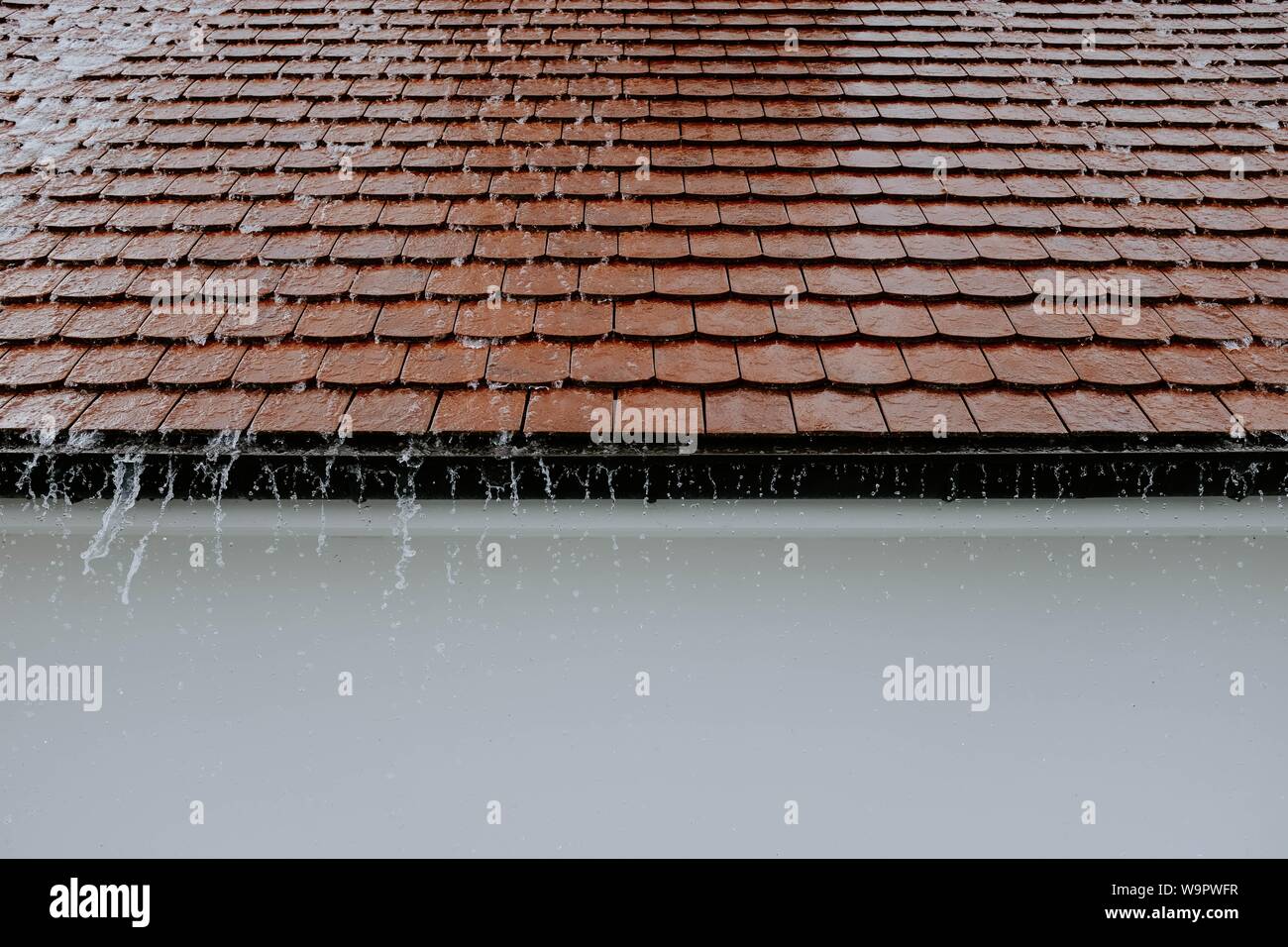 Wide shot of wet roof tiles with water flowing down Stock Photo - Alamy