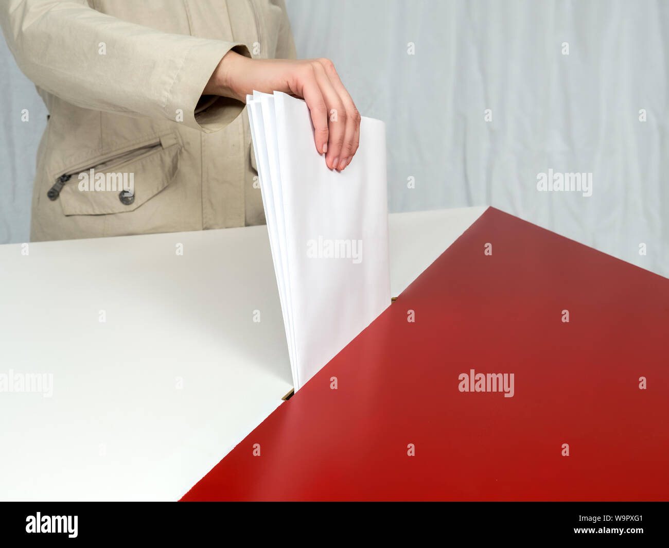 Female voter casting a vote into ballot box during election to the ...