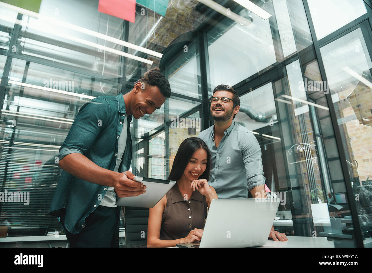 Happy to work together. Group of three young and positive employees ...