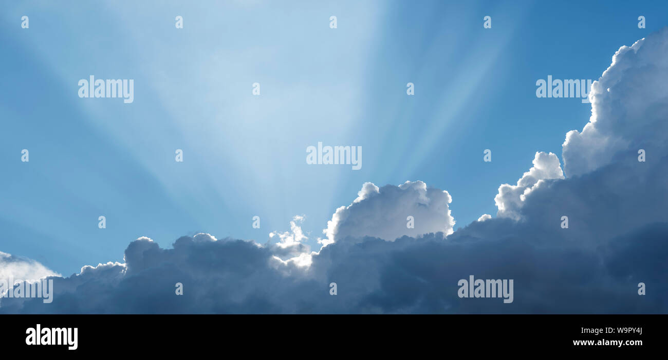 Light streaming from behind a cumulus cloud in a blue sky for ...