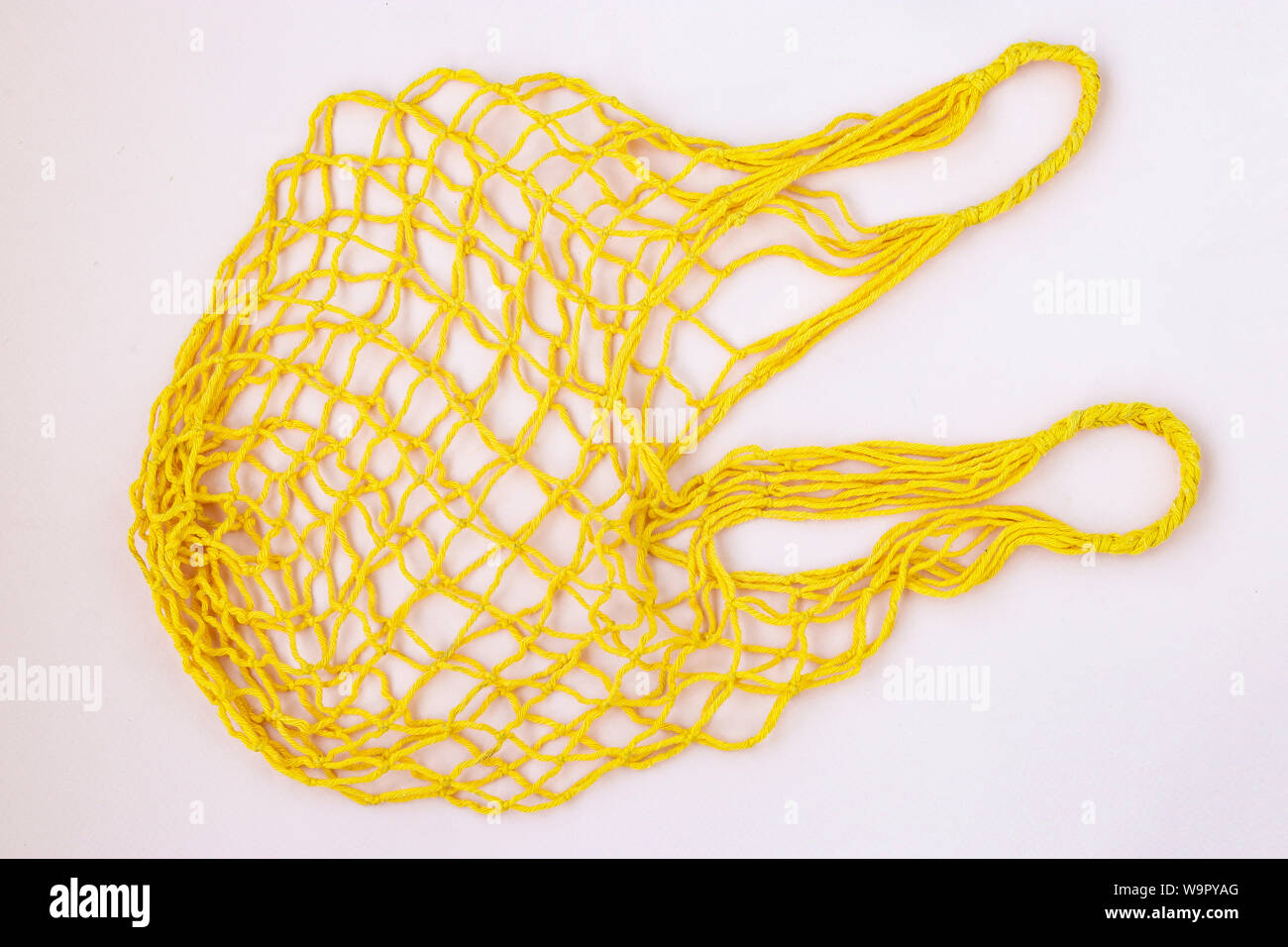 Empty reusable shopping yellow mesh bag on white background, horizontal ...