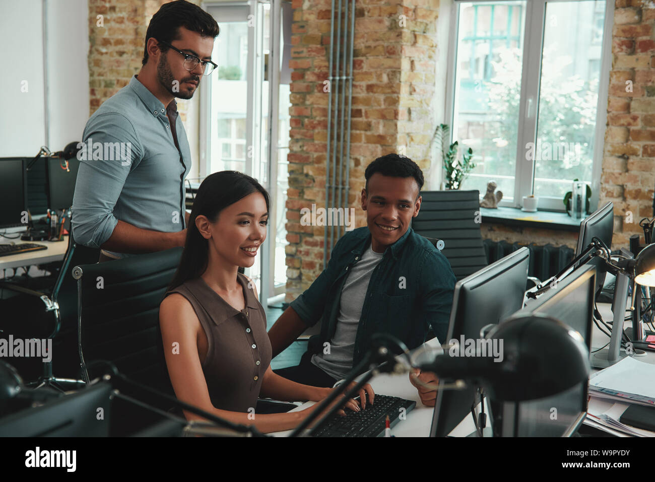 Daily routine. Group of young employees working on computers and ...