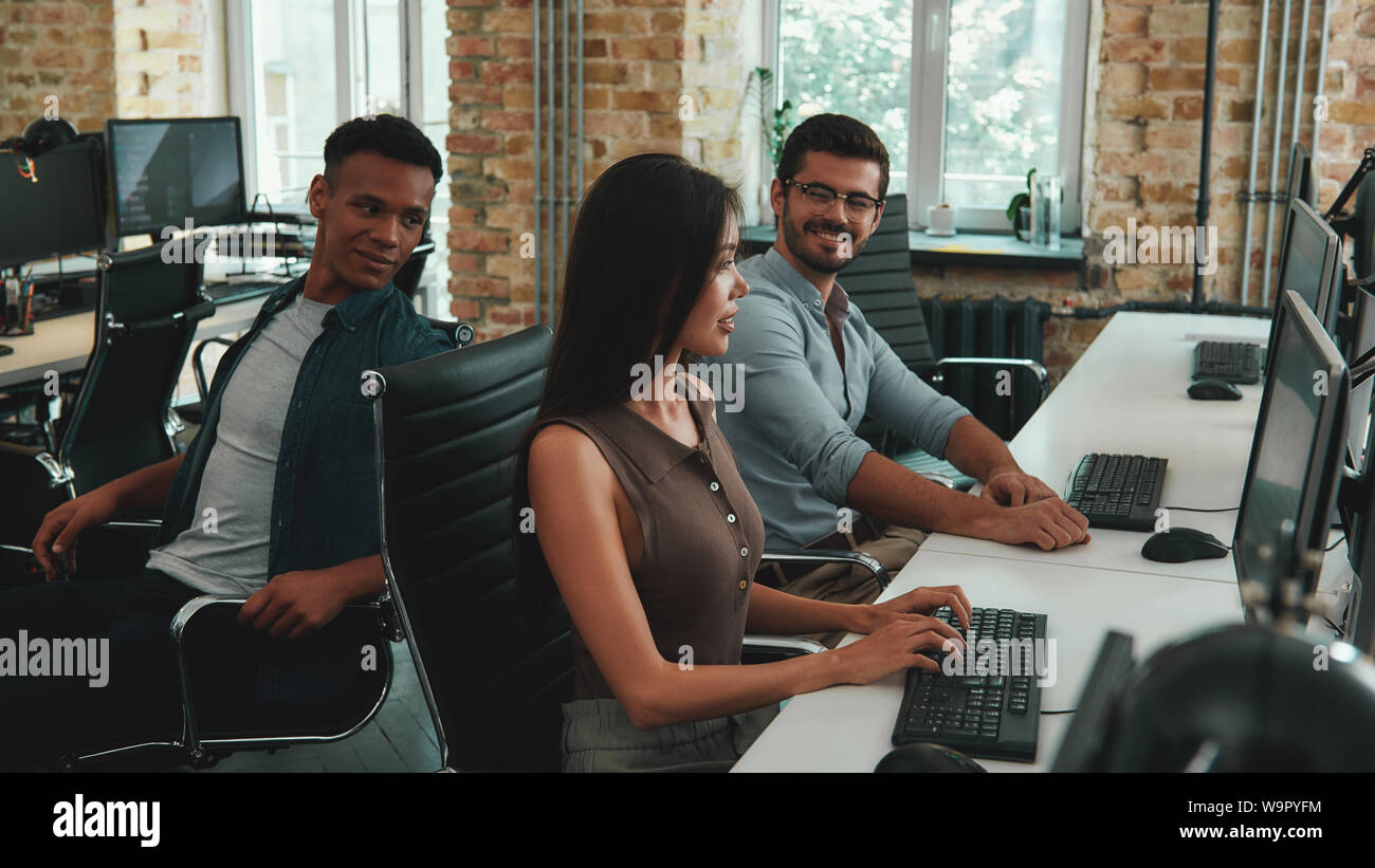 Project team. Group of cheerful young employees working on computers ...