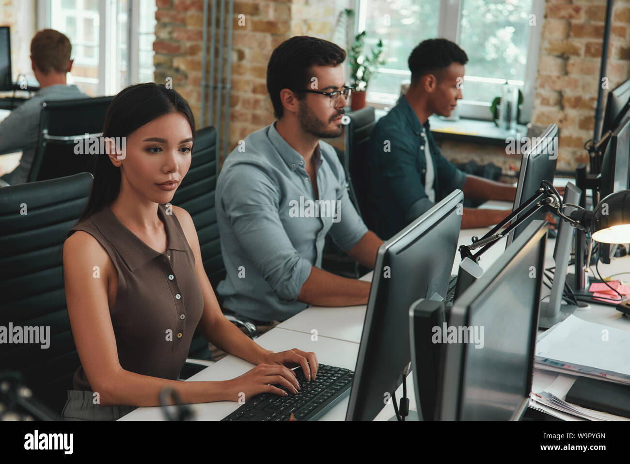 Daily routine. Group of young employees working on computers while ...