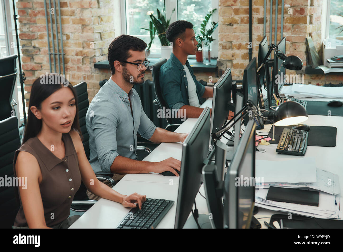 Teamwork . Group of young employees working on computers while sitting ...
