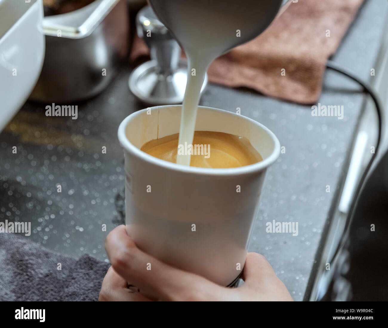 The production of coffee is about to be completed. Pour milk into the ...