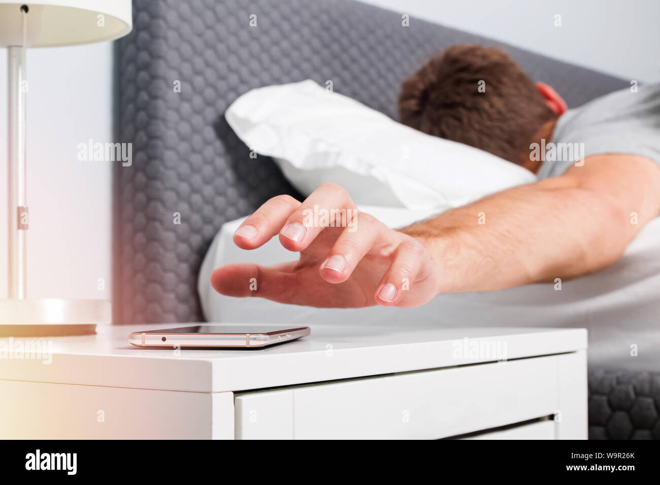Man's hand close-up trying to reach out ringing cell phone or alarm to ...