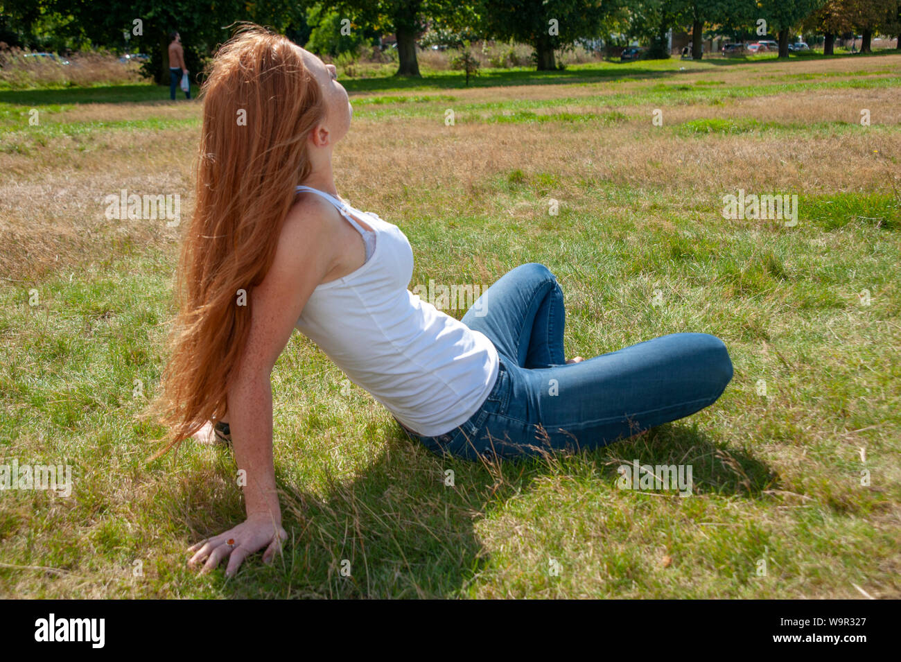 Tennage Girl Red Hair Freckles Sits Back On Grass Relaxed Face To Sun