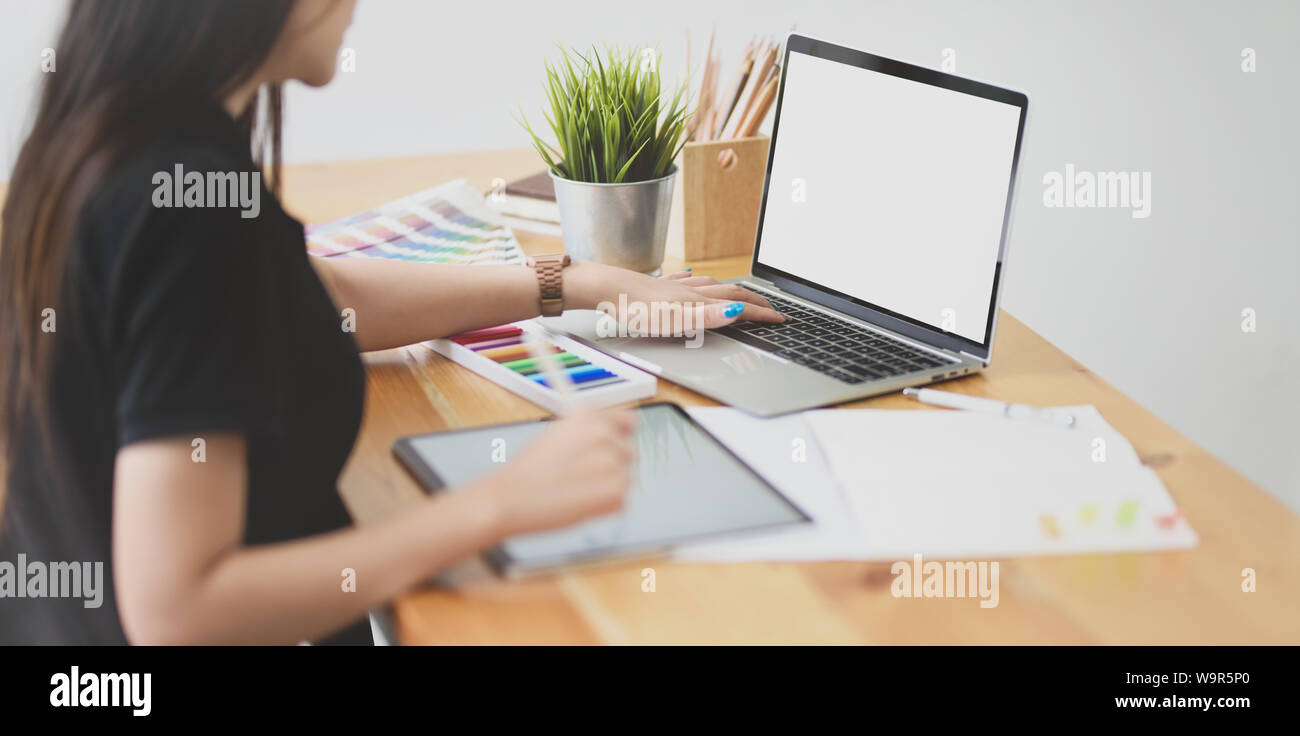 Young female designer working on her concept with blank screen laptop ...